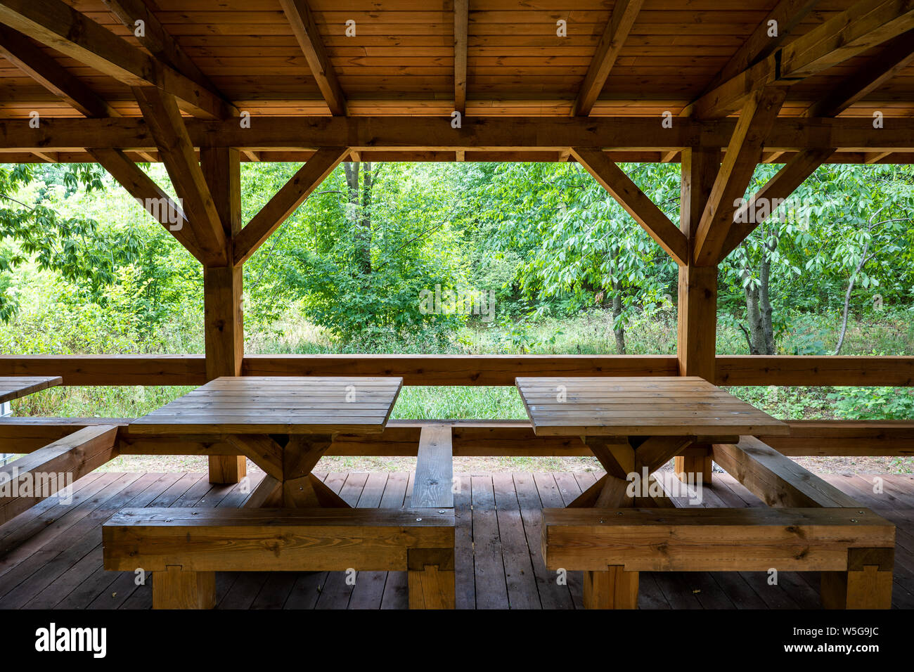 Shelter with wooden picnic tables and benches in a park Stock Photo - Alamy