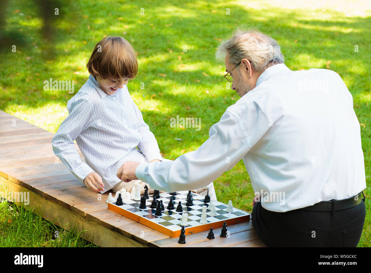 Grandfather, father and kids playing chess in summer garden. Grandpa ...