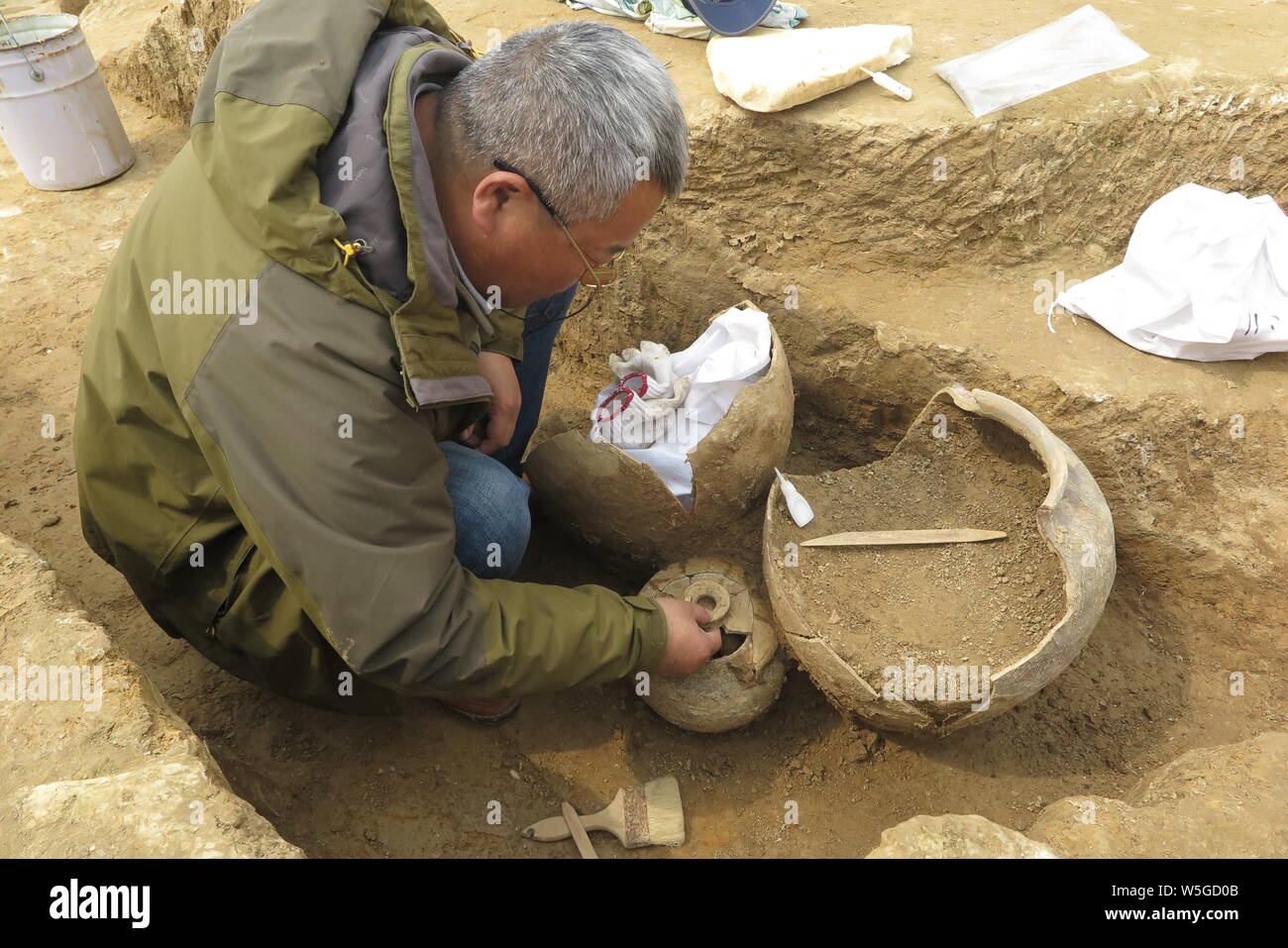 A Chinese archaeologist lifts the lid to open a jar filled with 2500 ...