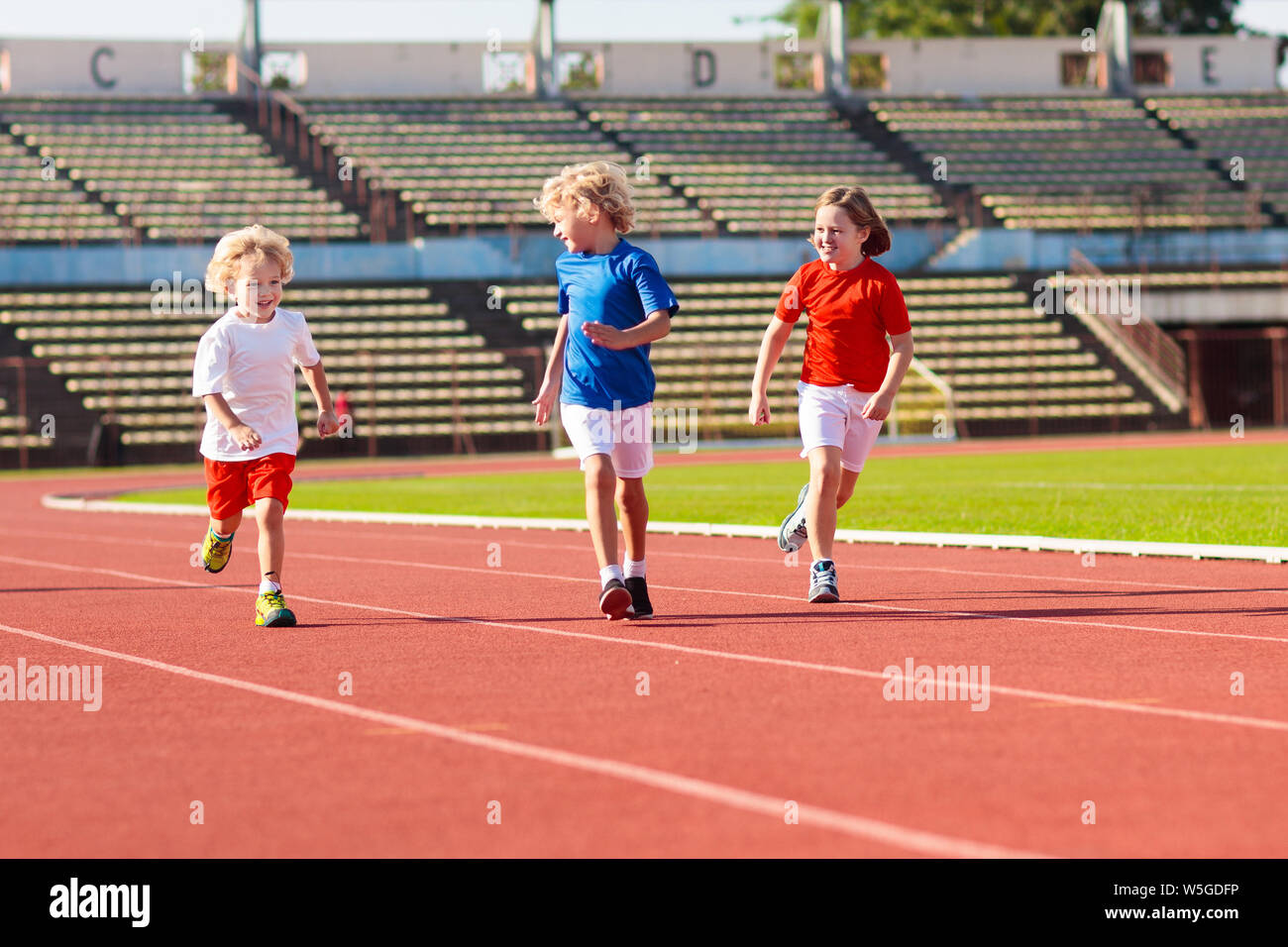Child running in stadium. Kids run on outdoor track. Healthy sport ...