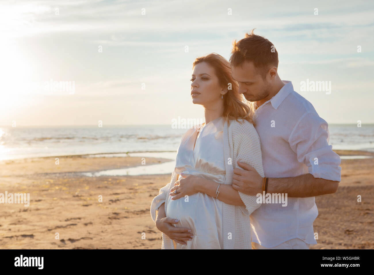 Romantic walk on the beach, waiting for a baby. Happy young couple ...