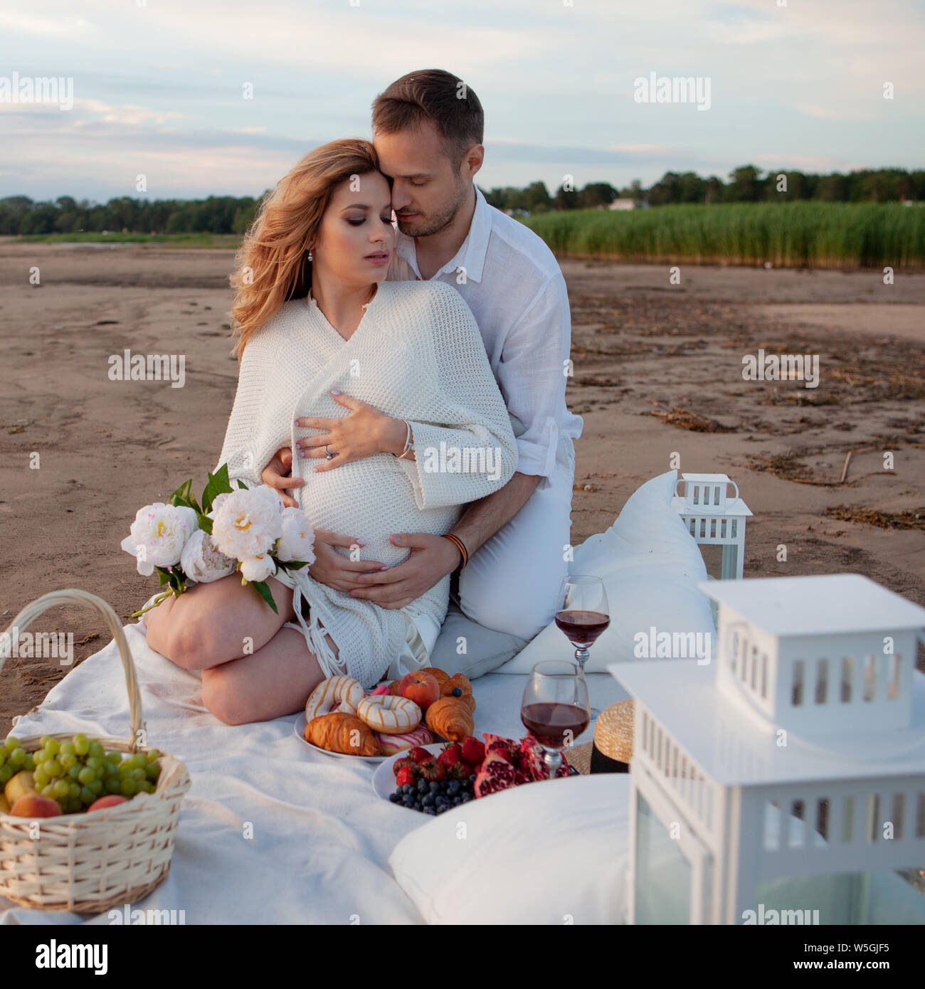 Picnic, love, tenderness. The couple sits on a plaid with pillows ...