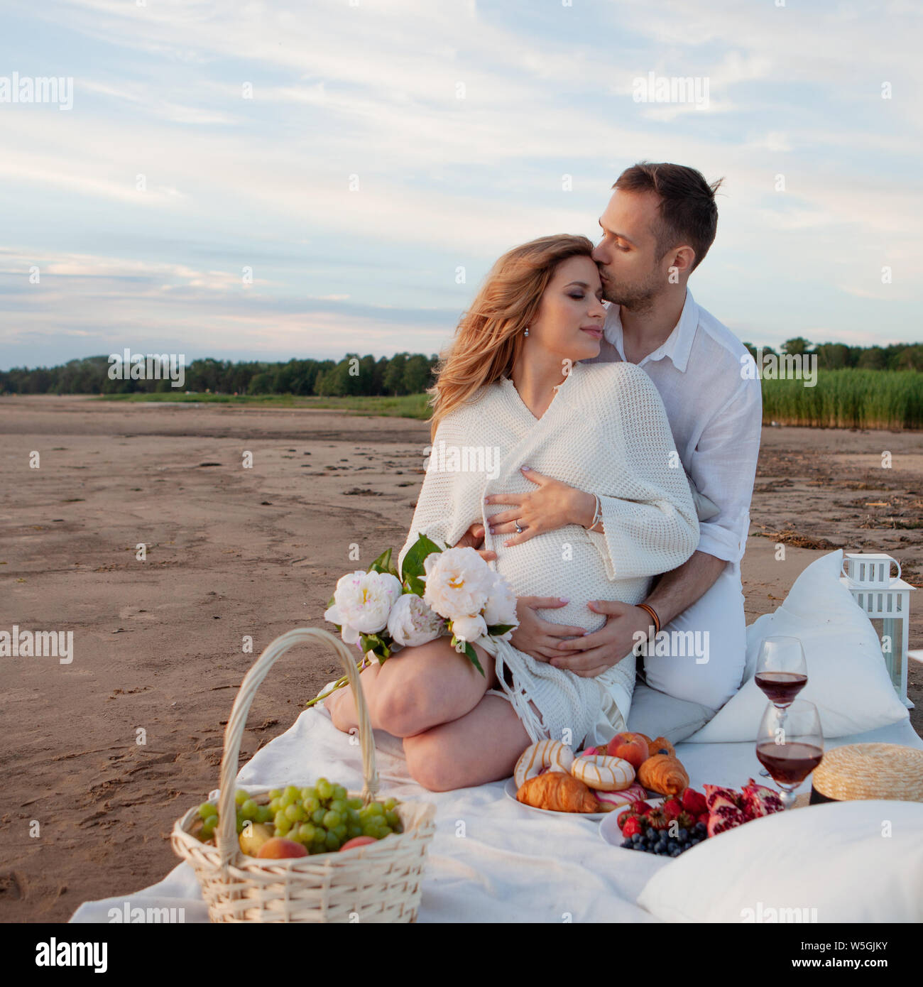 Picnic, love, tenderness. The couple sits on a plaid with pillows ...