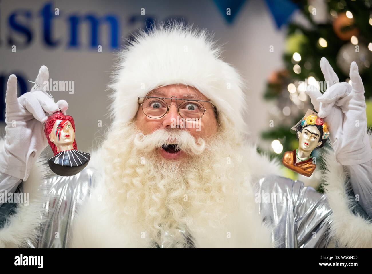 A man dressed as Future Fantasy Santa holds David Bowie (left) and ...