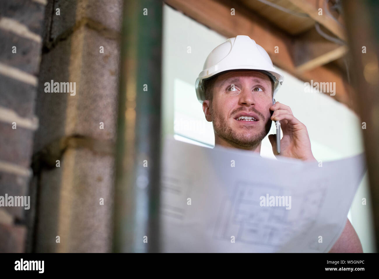 Architect Inside House Being Renovated Studying Plans Talking On Mobile ...