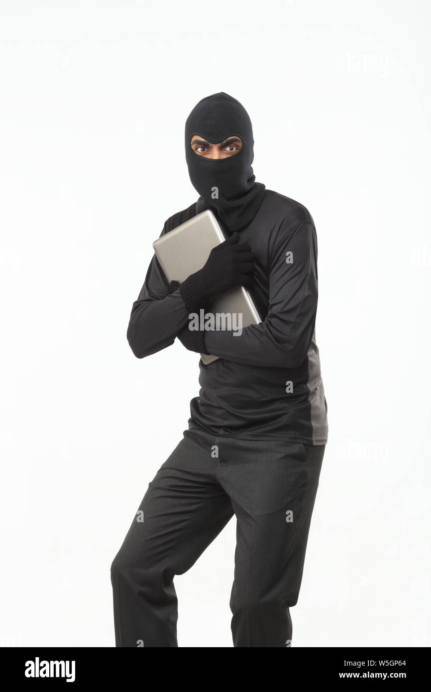 Hacker standing with a laptop Stock Photo - Alamy