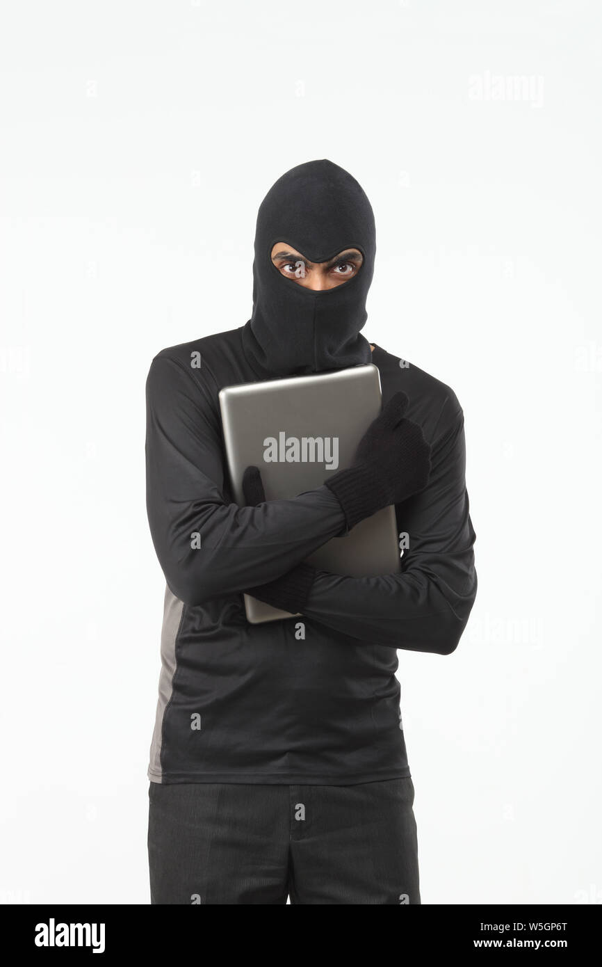 Hacker standing with a laptop Stock Photo - Alamy