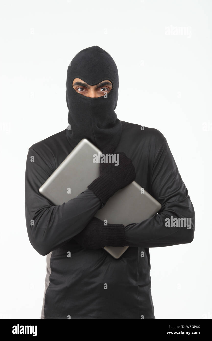 Hacker standing with a laptop Stock Photo - Alamy