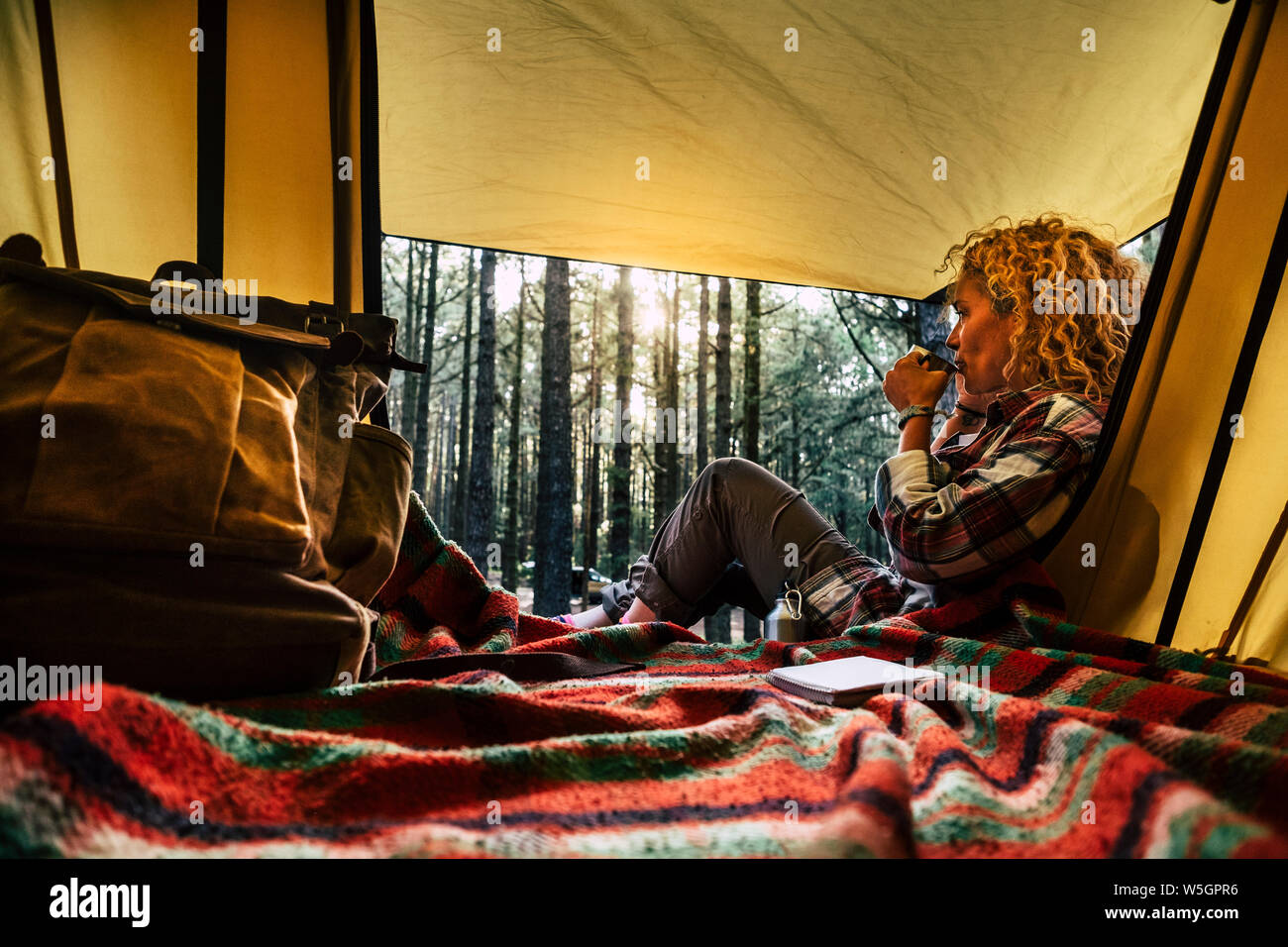 Independent beautiful curly blonde hair woman sit down outside a tent ...