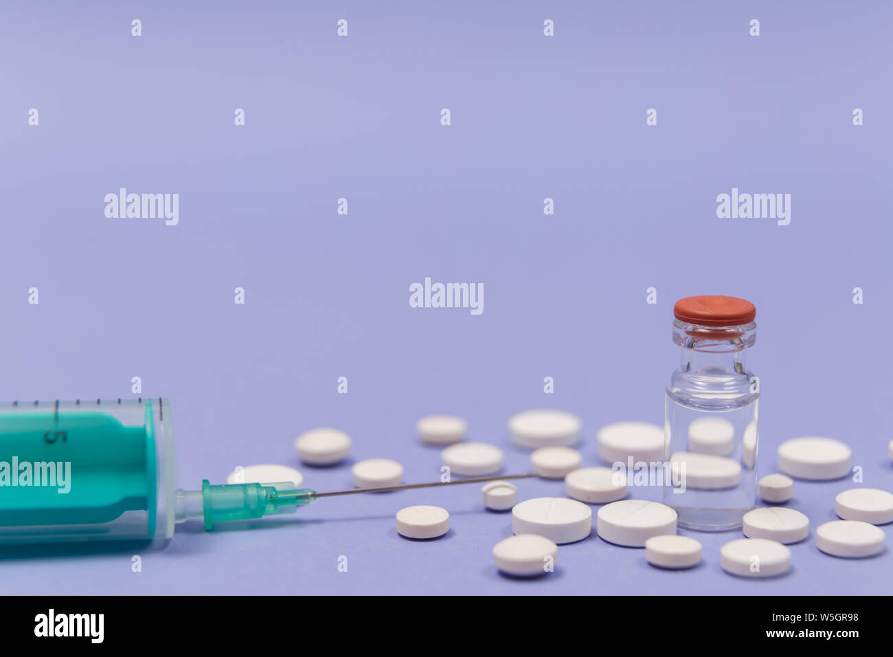 Pill and injection bottle on a purple background with copy space ...