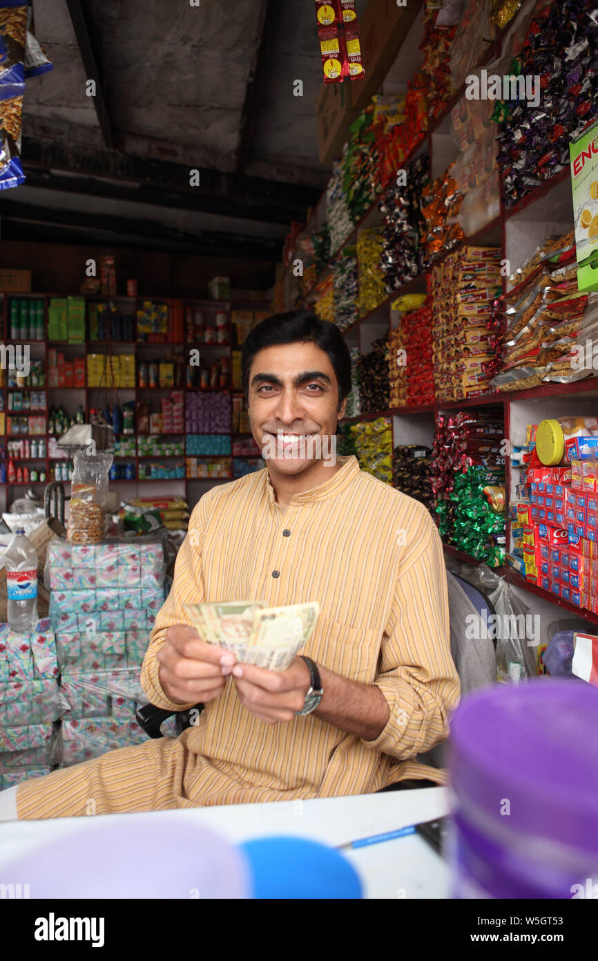 Shopkeeper counting money in grocery shop Stock Photo - Alamy