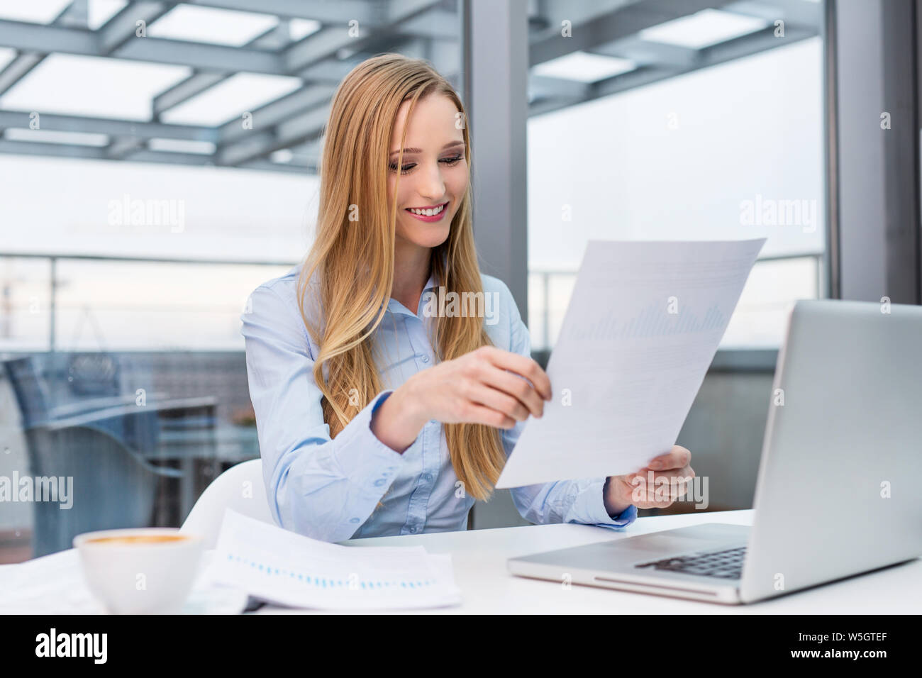 Happy businesswoman reading business report Stock Photo - Alamy