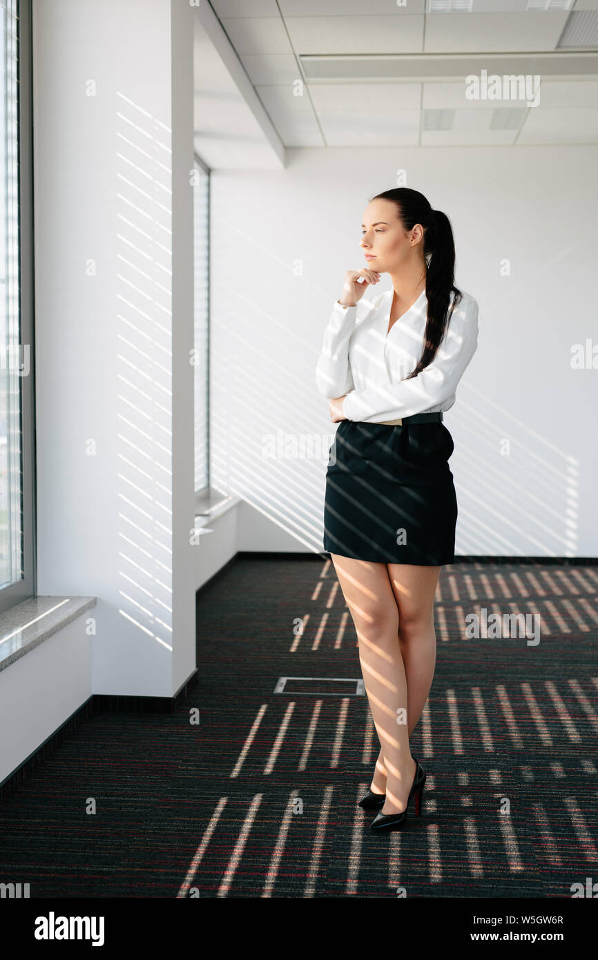 Photo of a female executive standing by a window and thinking Stock ...