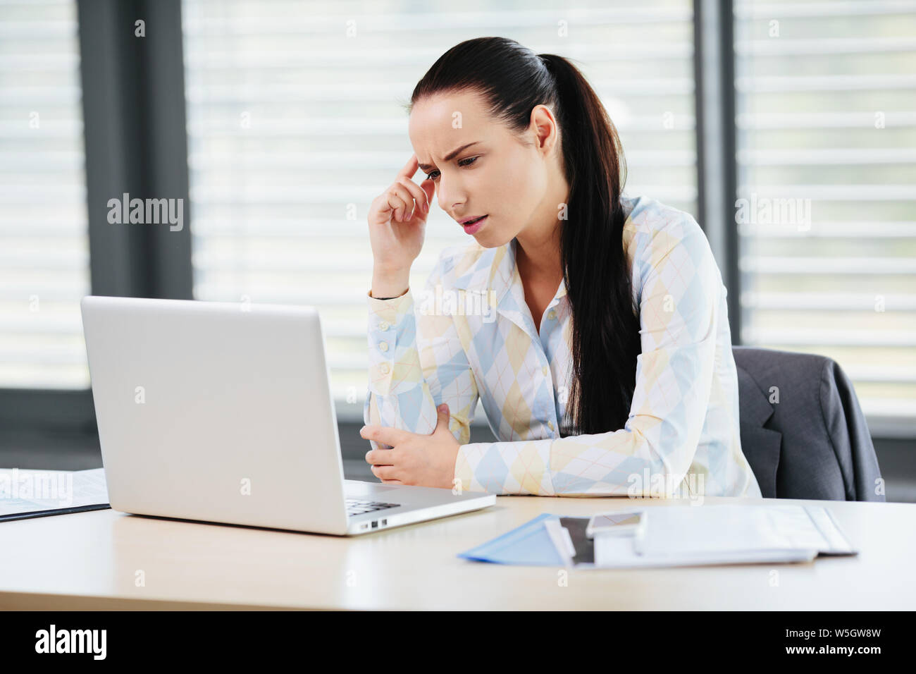 Photo of a an accountant looking at her laptop screen in confusion ...