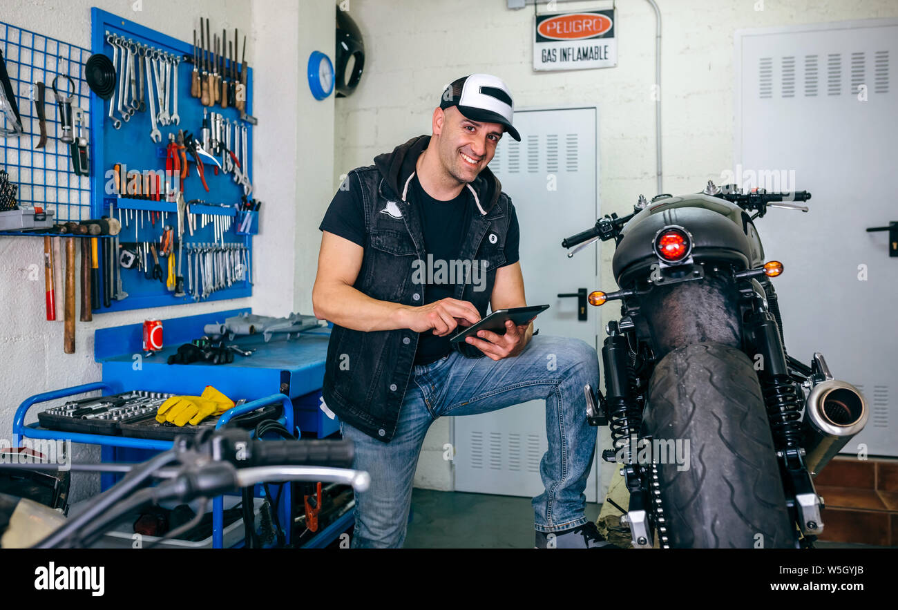 Mechanic checking custom motorcycle with tablet Stock Photo - Alamy