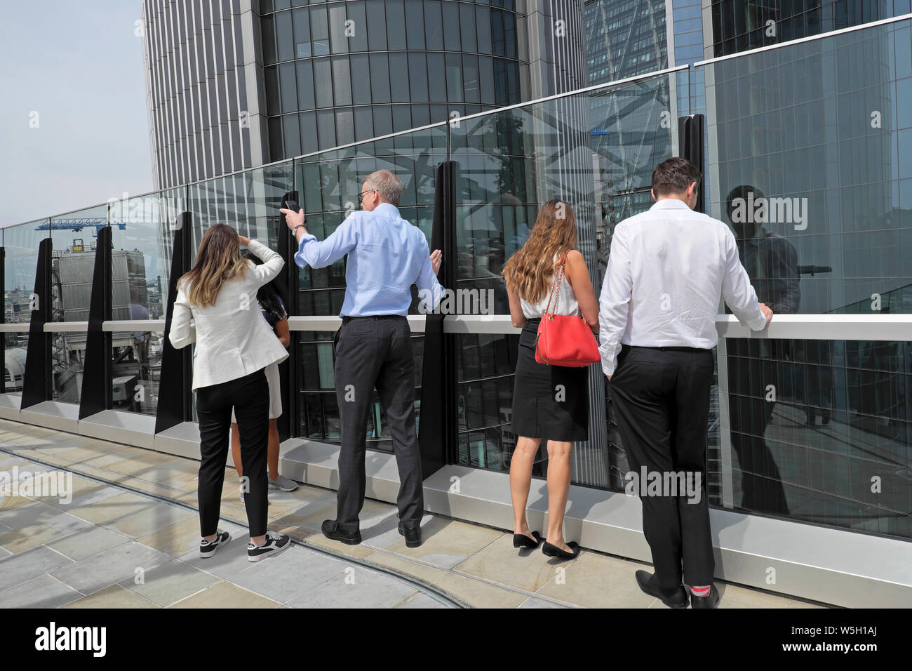 Office workers viewing buildings in the City of London from the roof ...