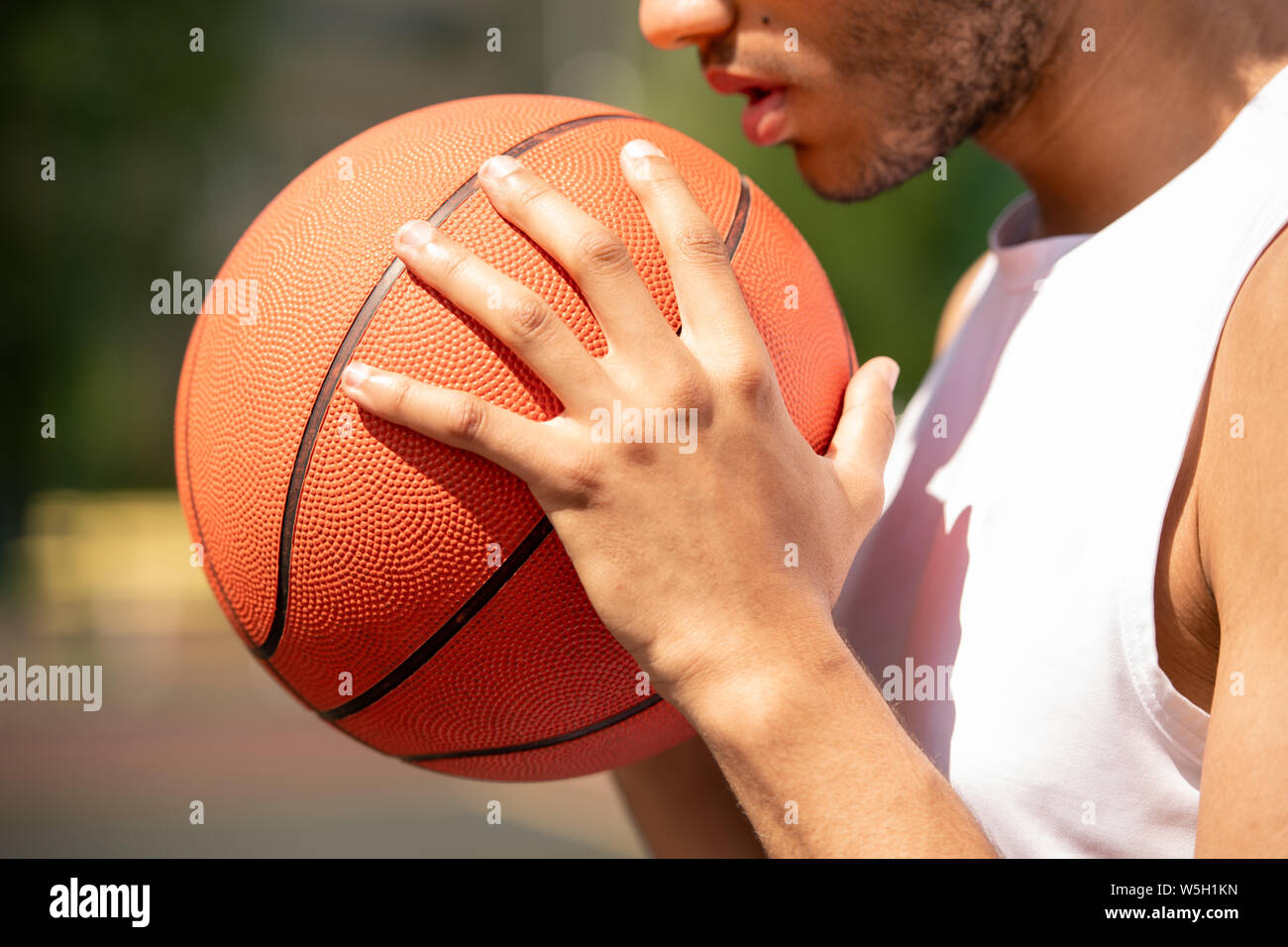 Young contemporary male basketball player holding ball by his face and ...