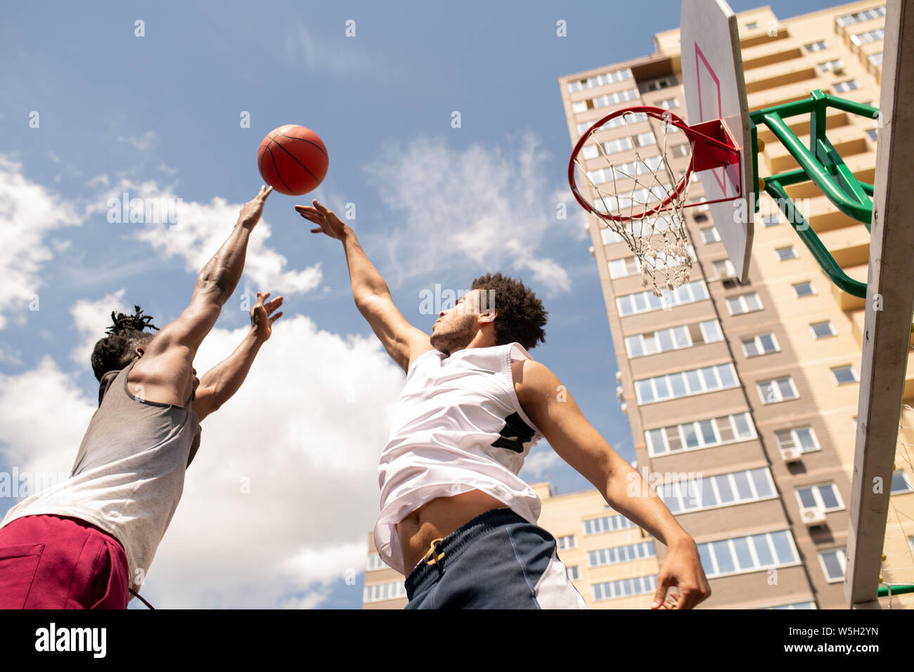 Below view of two intercultural rivals trying to catch ball in motion ...