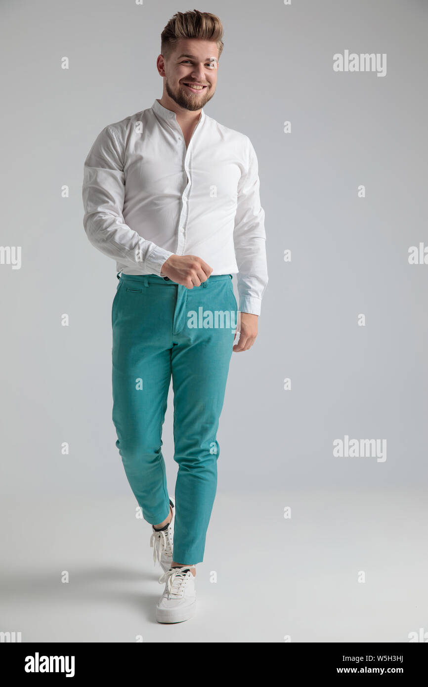 Happy young man stepping forward and laughing while wearing jeans and ...