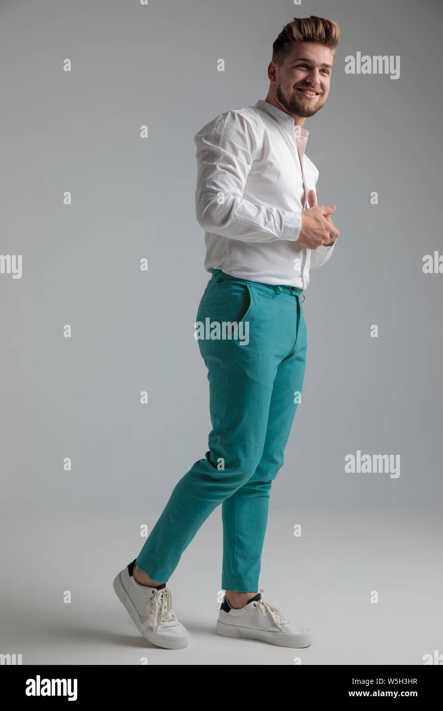 Positive young man posing and playing with his hands while laughing and ...