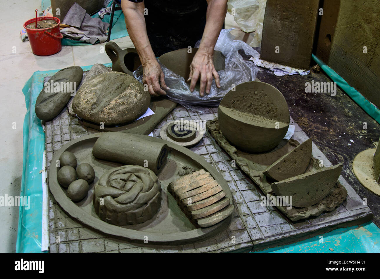 Hands of artists with clay working and creating outflows of fruits ...