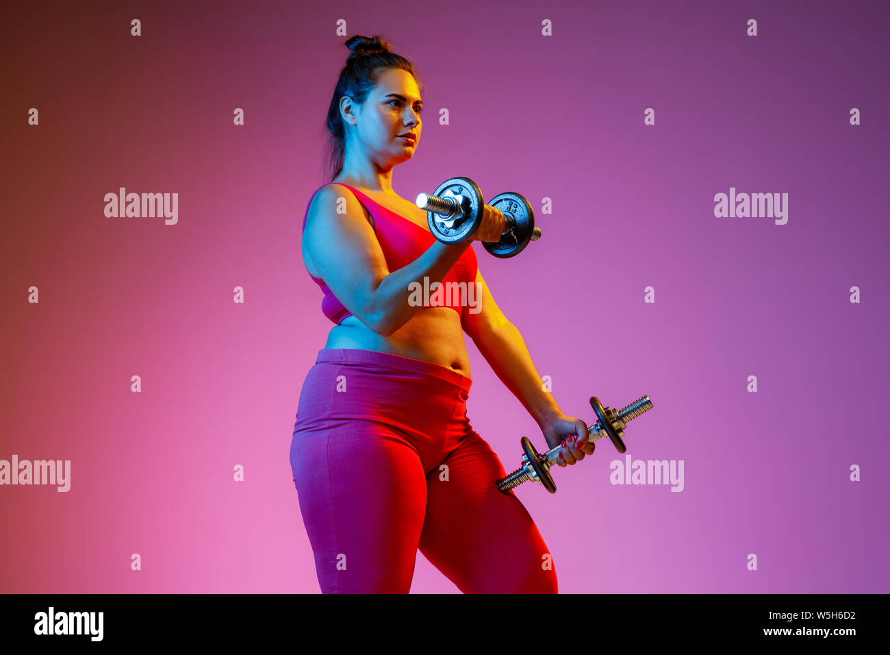 Young caucasian plus size female model's doing exercises on gradient ...
