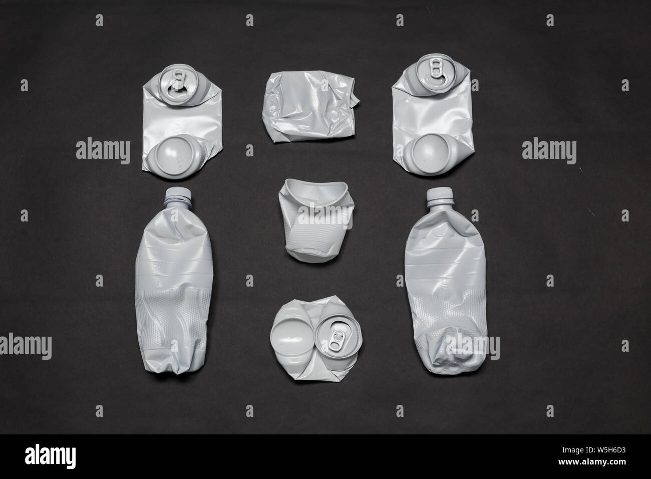 Crumpled plastic and metal cans lie on a black background. Concept of ...