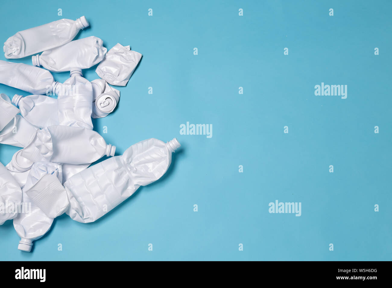Crumpled plastic and metal cans lie on a blue background with copy ...