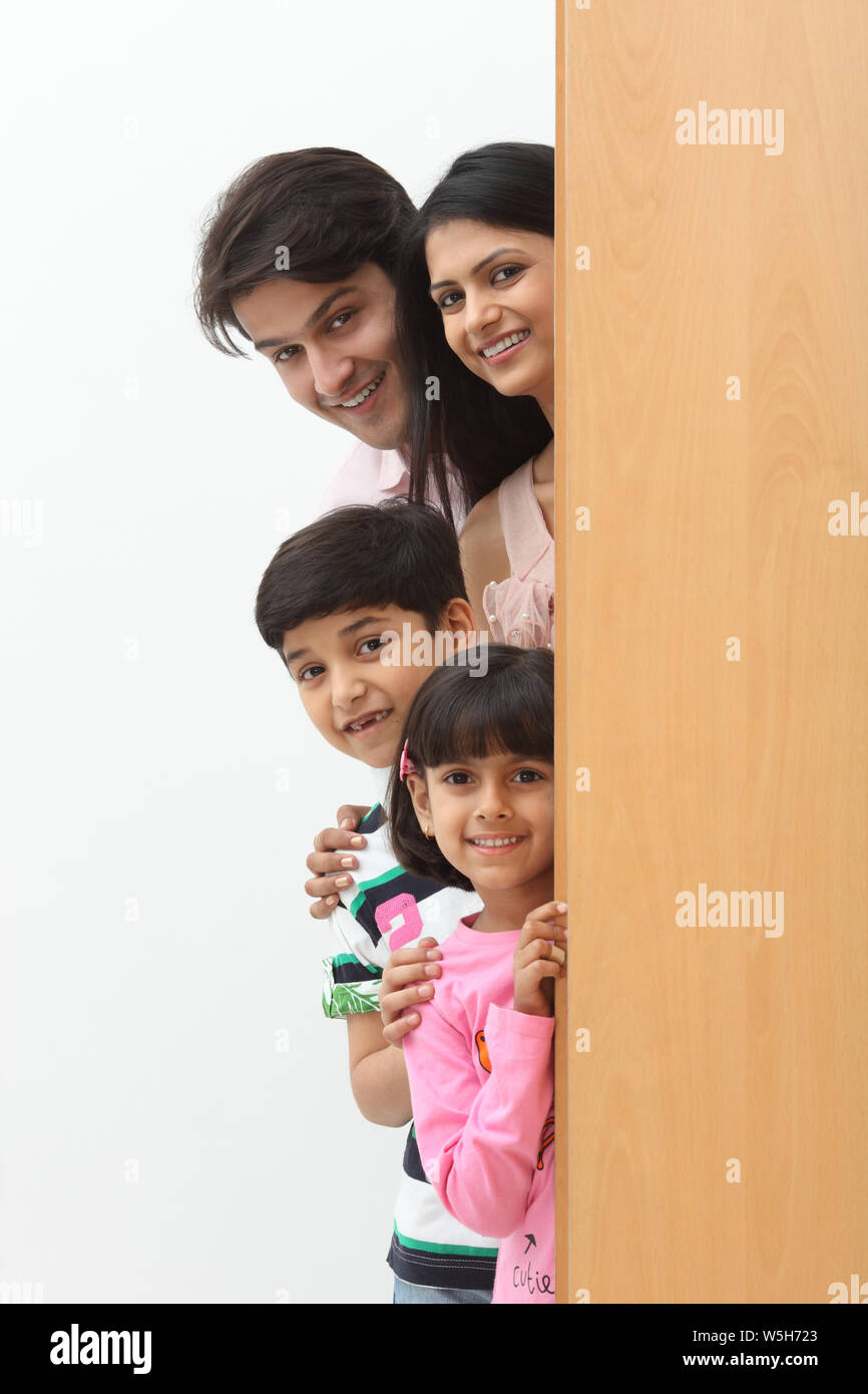 Family peeking out from behind plank Stock Photo - Alamy