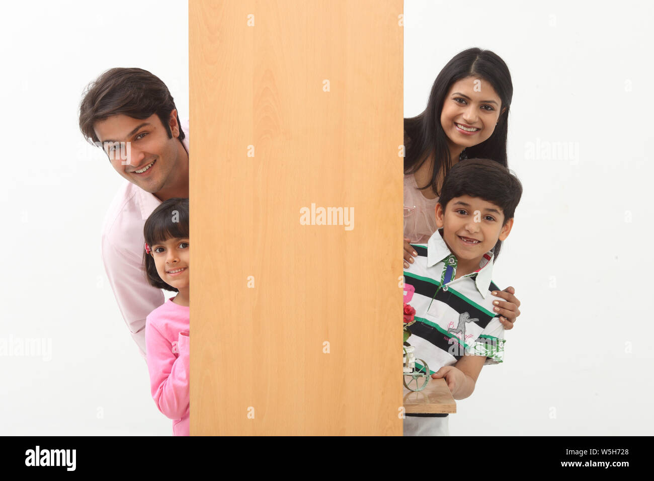 Family peeking out from behind plank Stock Photo - Alamy