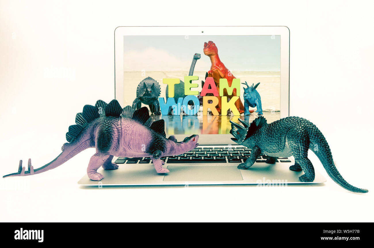 dinosaur toys learning about TEAM WORK on a laptop isolated on white ...