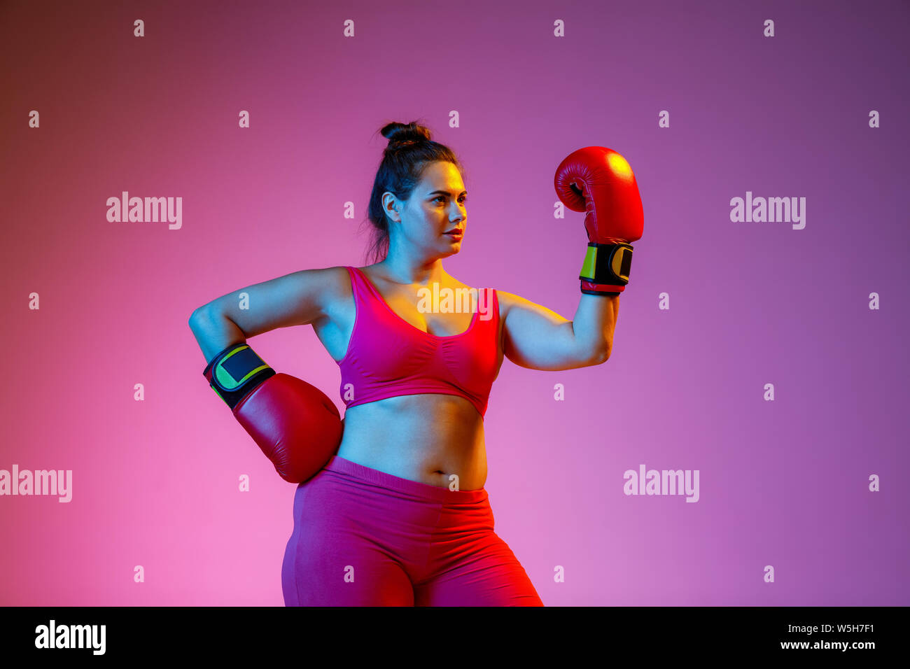 Young caucasian plus size female model's doing exercises on gradient ...