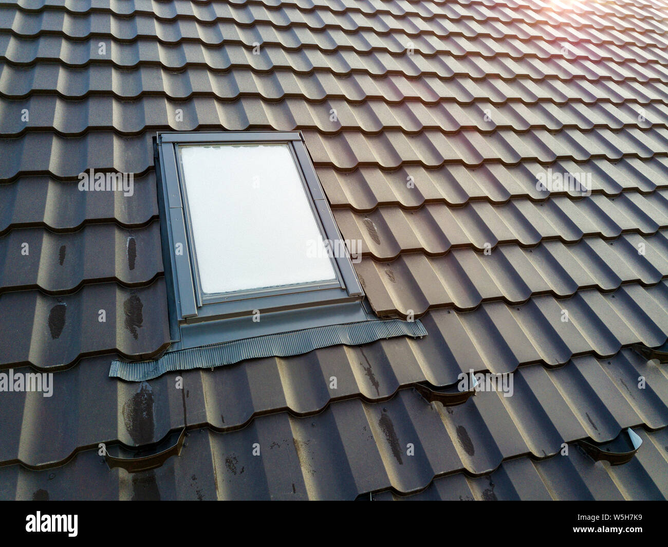 Close-up of new attic plastic window installed in shingled house roof ...