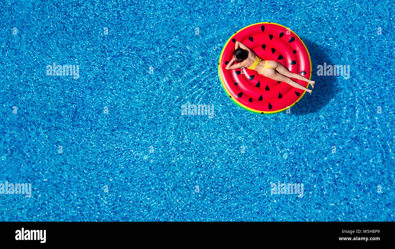 Aerial View Of Female In Bikini Lying On A Floating Mattress In Swimming Pool In Swimming Pool