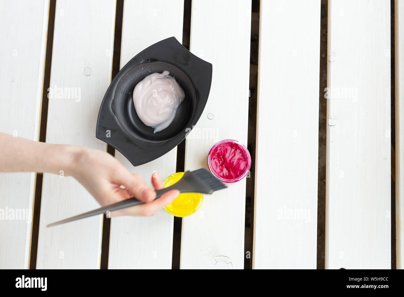 Coloring and hair stylist concept - hands of hairdresser is mixing a ...