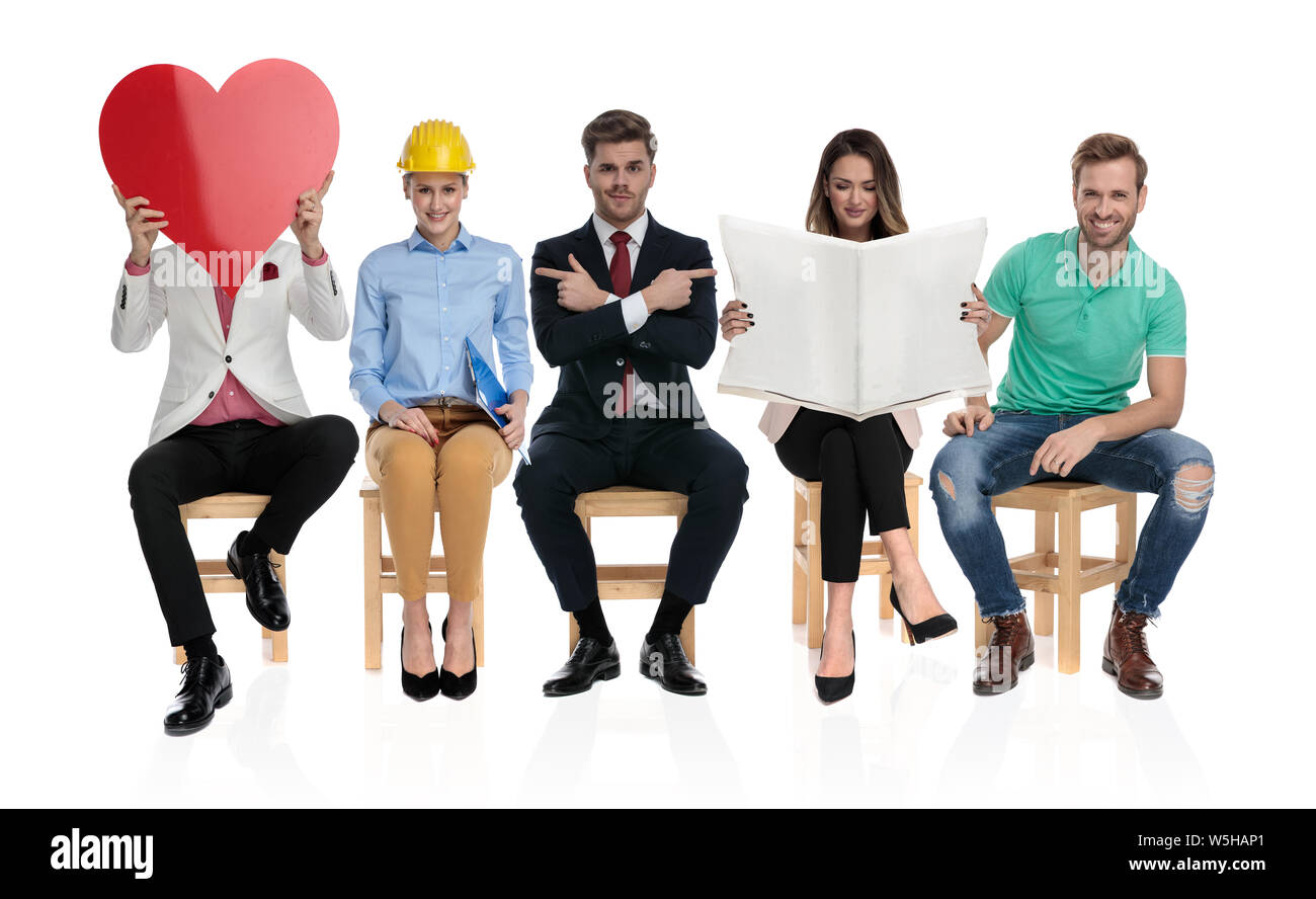 five young people having fun at a job interview waiting on chairs on ...