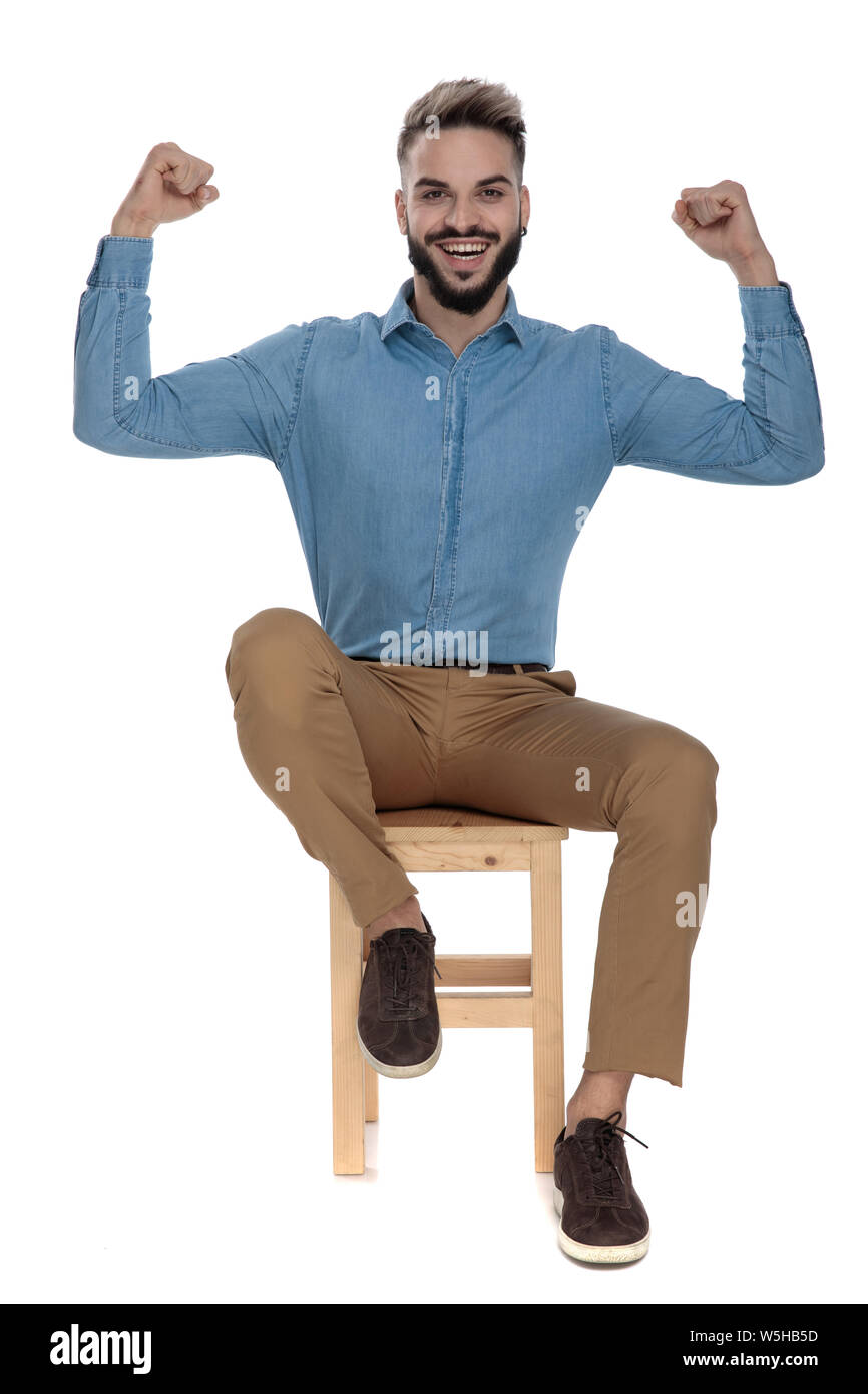 model man sitting with fists up in the air showing his muscles on white ...