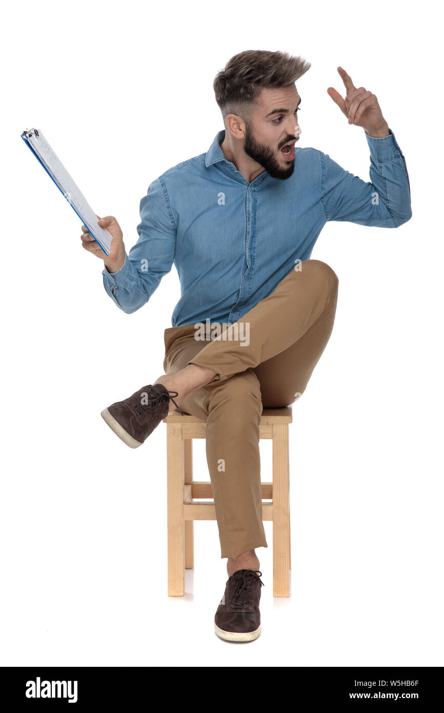 seated attractive man screaming with a clipboard in his hand on white ...