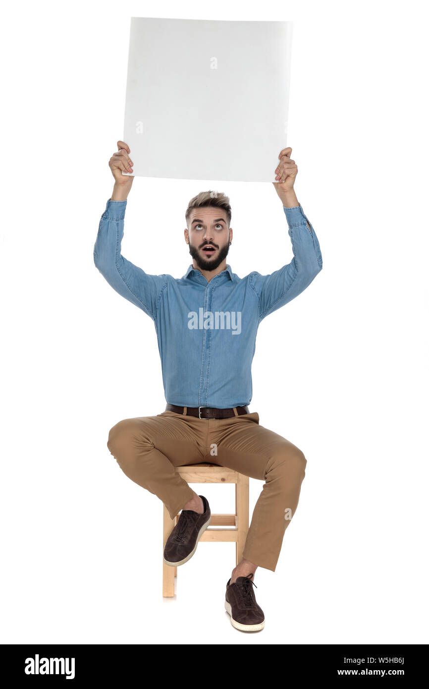 seated fool man in blue jeans shirt holds an empty billboard up in the ...