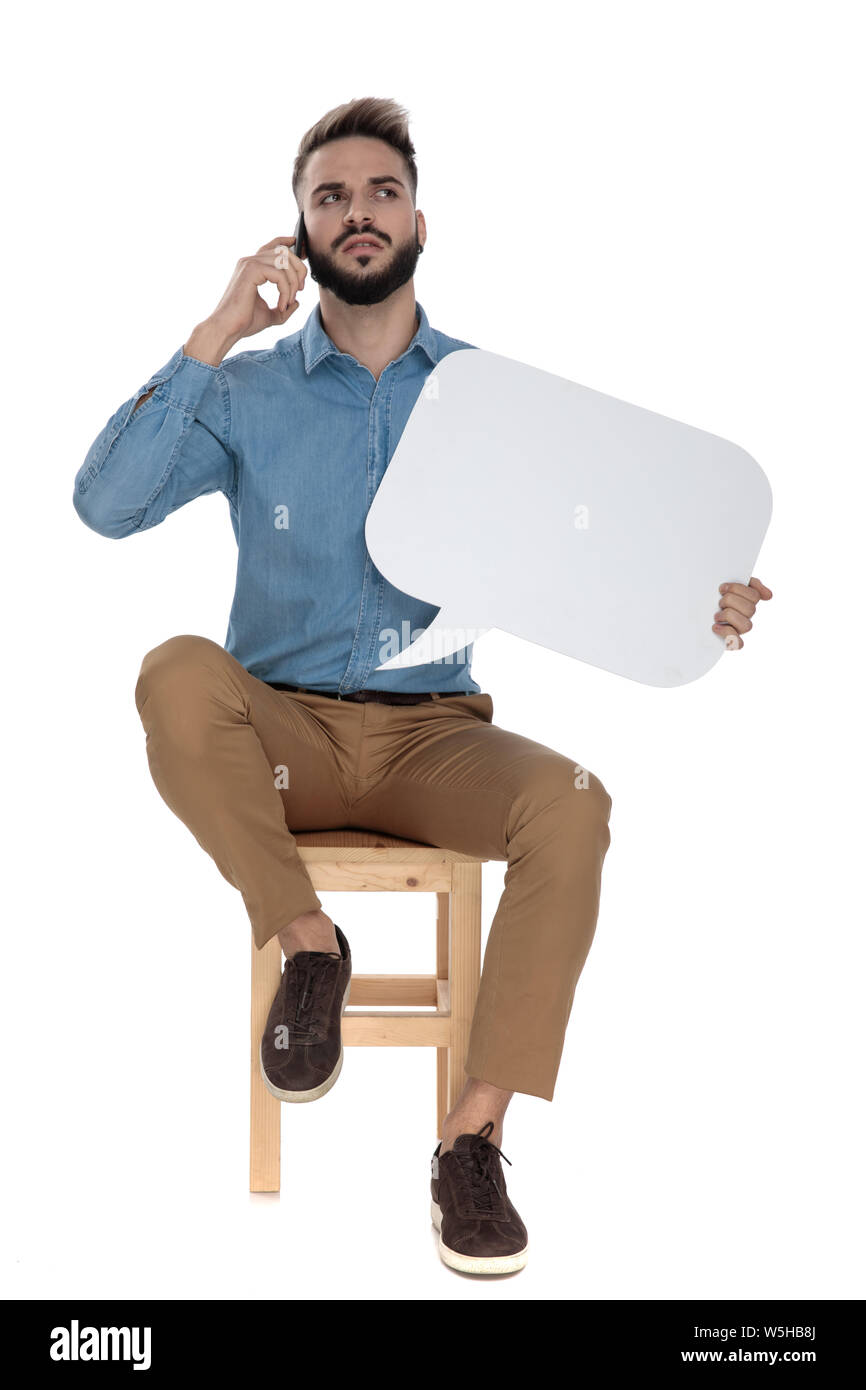 seated intrigued man in blue jeans shirt talking on the phone while ...