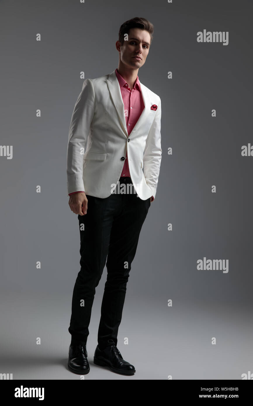 smart guy in suit standing with hand in pocket on grey background Stock ...