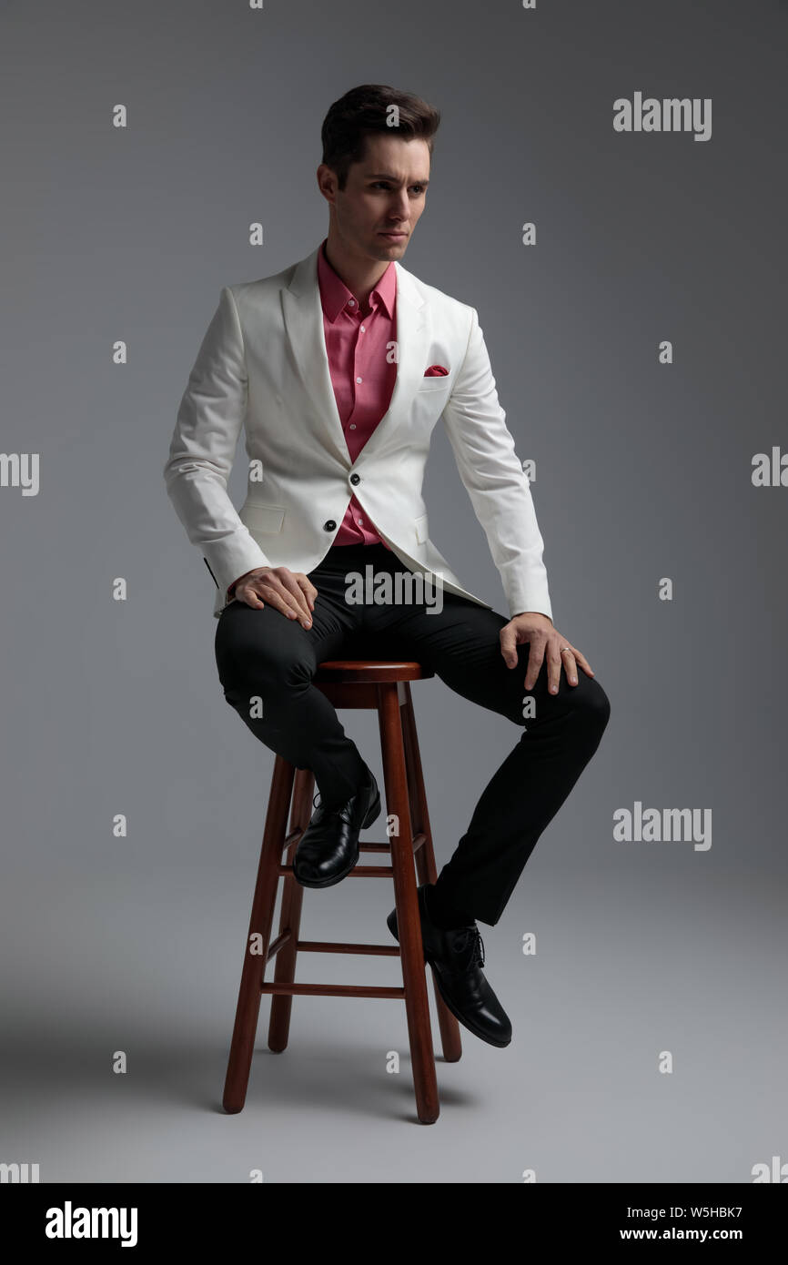 seated concentrated man in suit looking away while resting his hands on ...