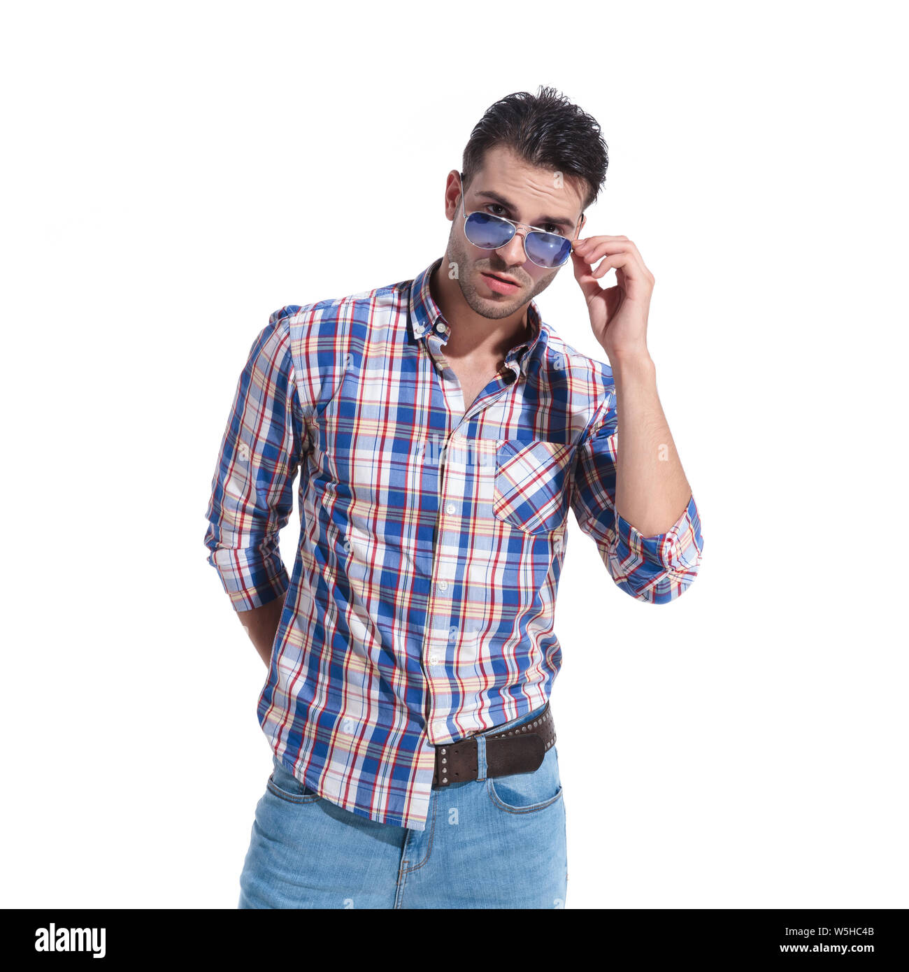 Curious man fixing his sunglasses and reaching for his back pocket ...