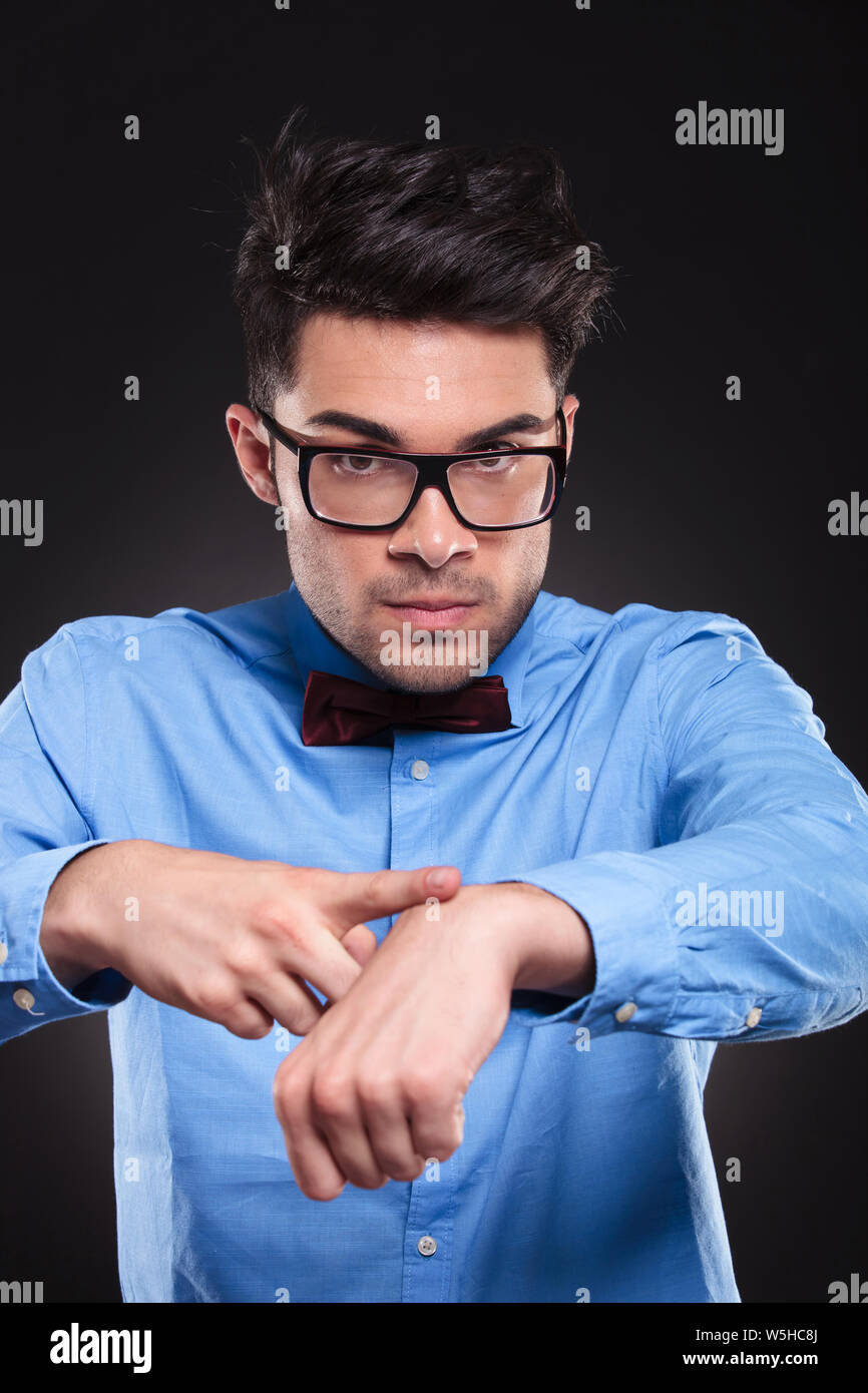 Upset young man pointing at imaginary watch and staring forward while ...