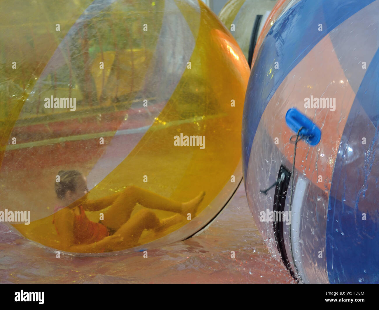 Kids having fun in inflatable bubble balls on water in amusement park ...