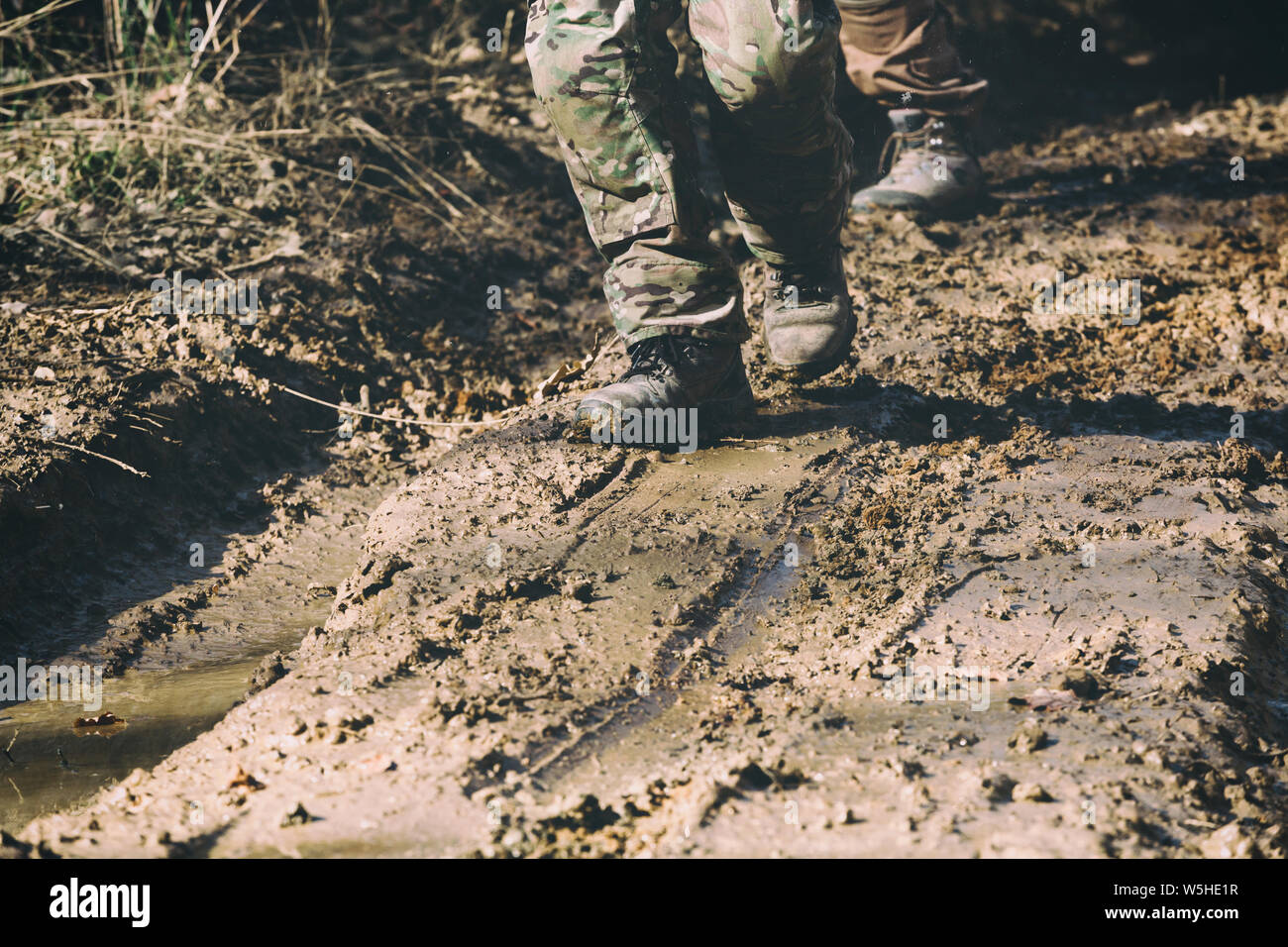 Brown military boots on mud and puddle Stock Photo - Alamy