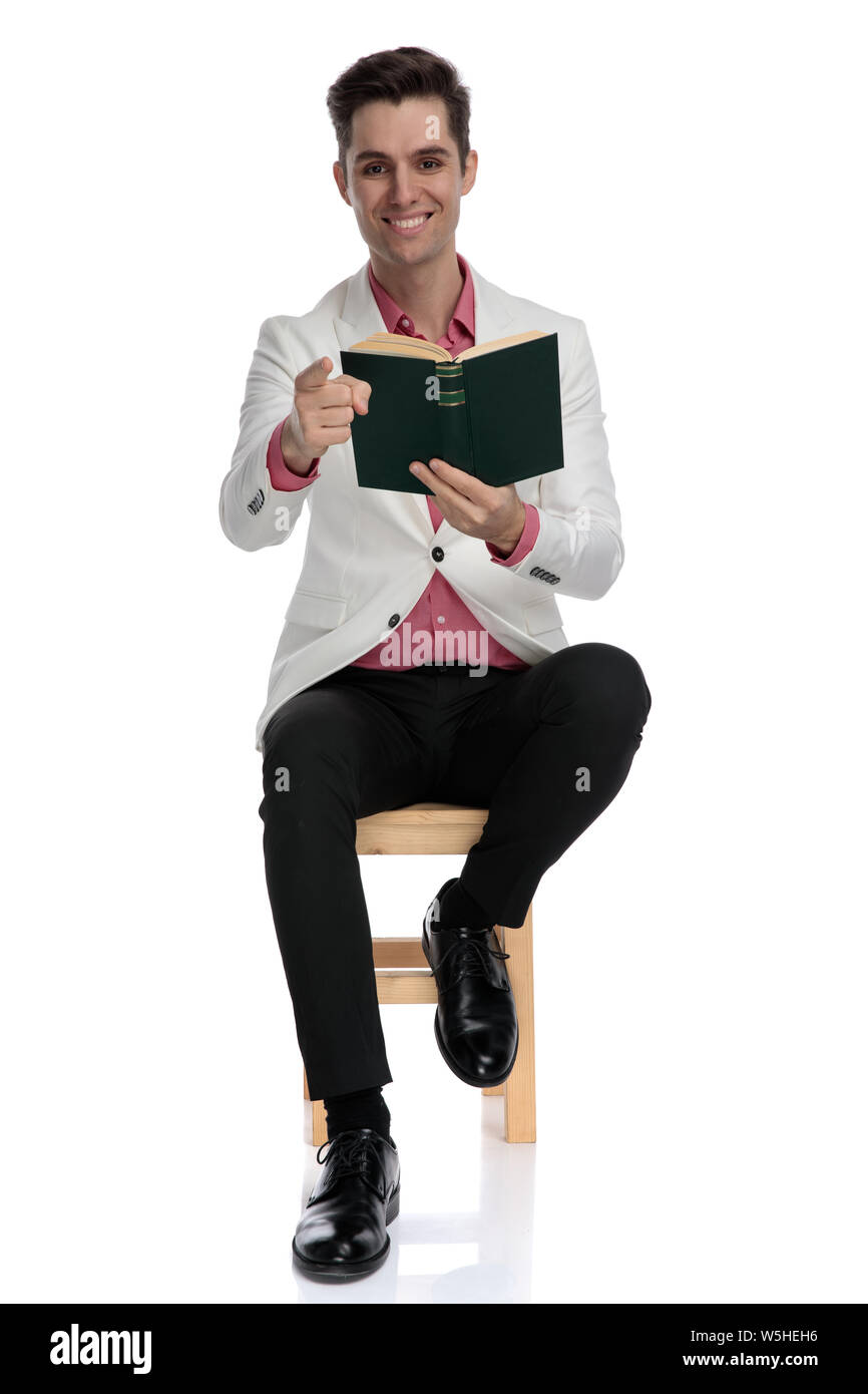 smiling smart casual man reading and pointing finger while sitting on a ...