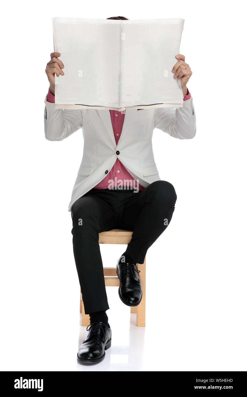 seated elegant man holding paper over his face, on white background ...