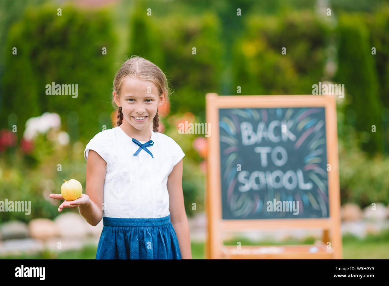 Happy schoolgirl with yellow apple background the chalkboard. Back to ...