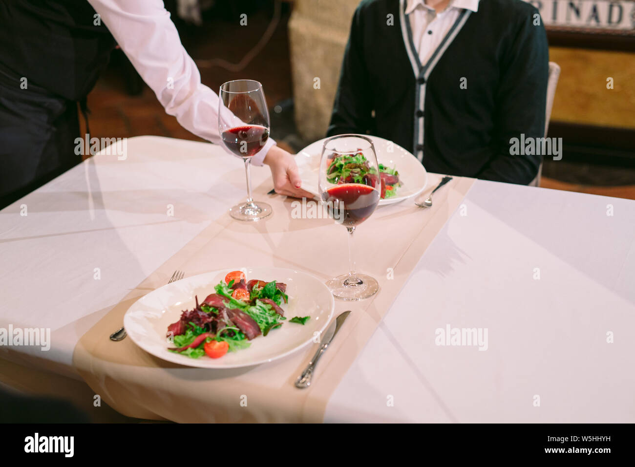 The waiter puts the salad on the table in front of the guest Stock ...